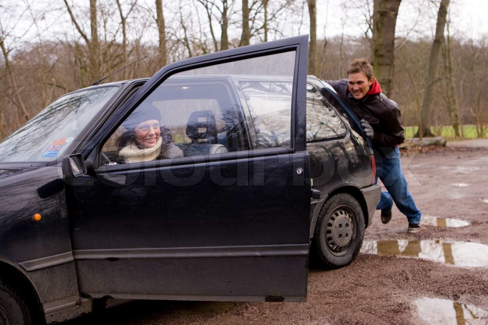 Man pushing a car on a muddy field | Stock image | Colourbox