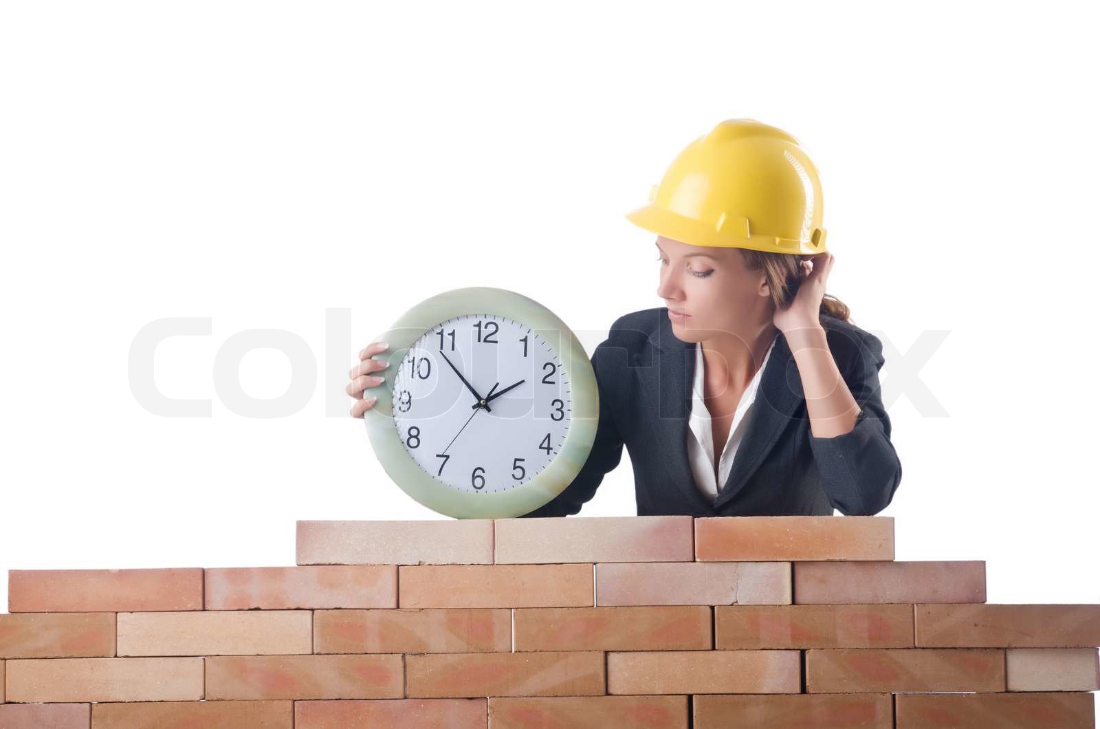 Woman construction worker with clock on white | Stock image | Colourbox