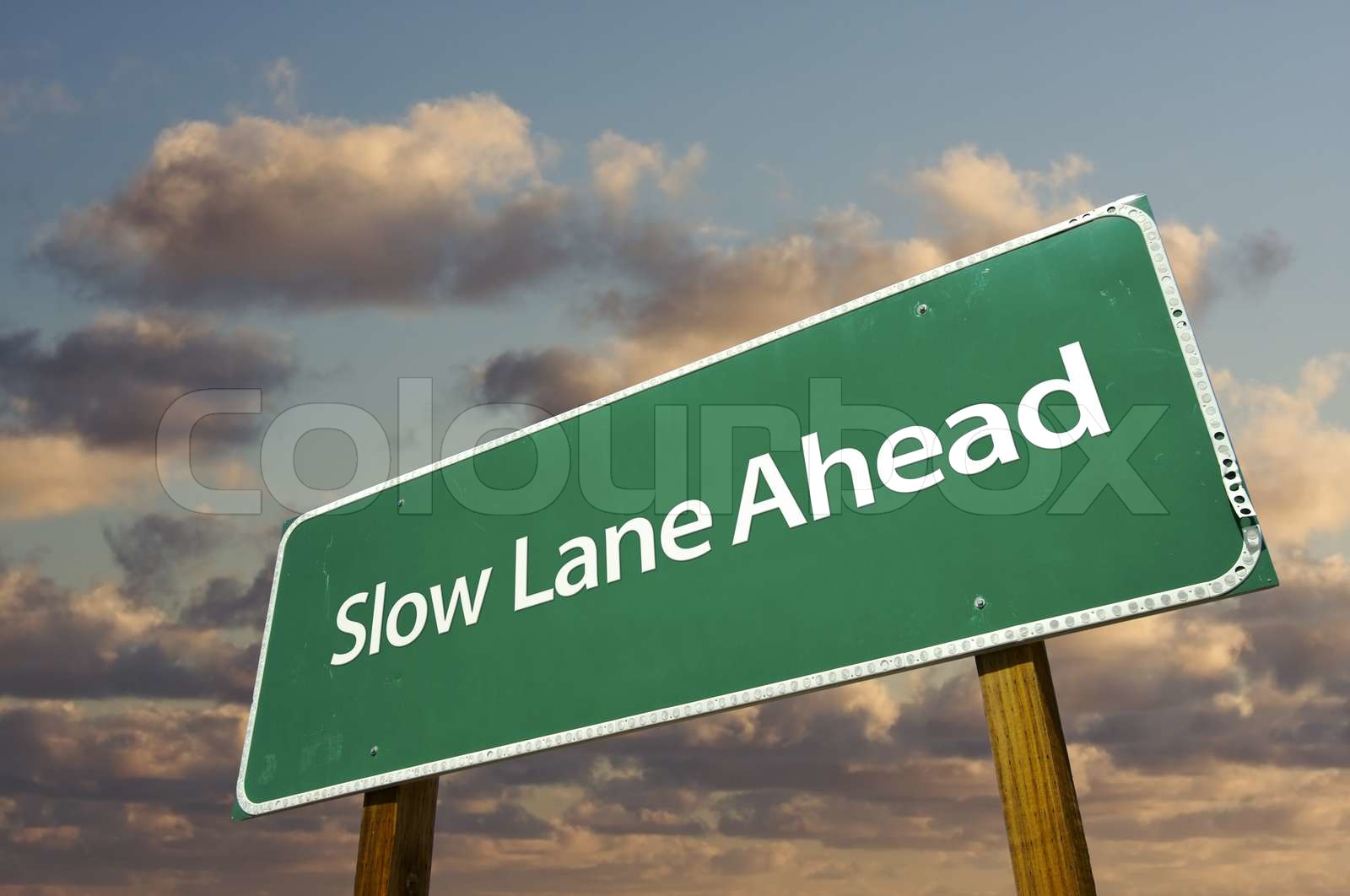 Slow Lane Ahead Green Road Sign Over Clouds | Stock image | Colourbox