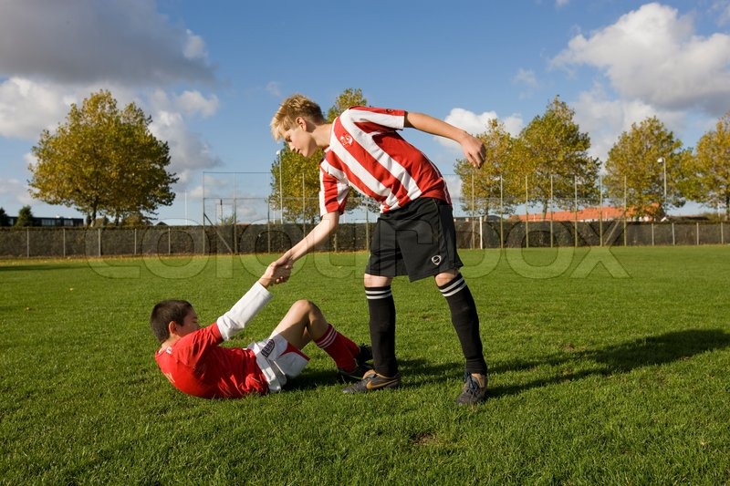 A young football player helping another ... | Stock image | Colourbox