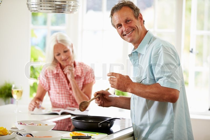 Middle Aged Couple Cooking Meal In Kitchen Together | Stock Photo ...