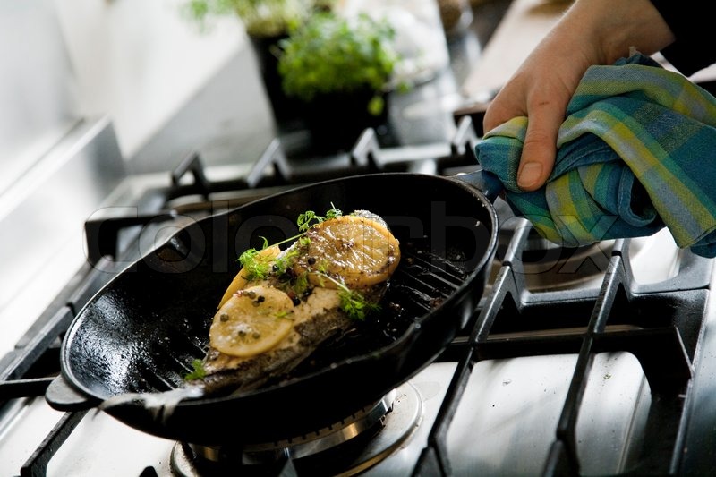 A woman frying fish on a gas stove | Stock image | Colourbox