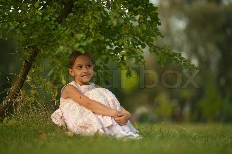 Little girl sitting under a tree in ... | Stock image | Colourbox