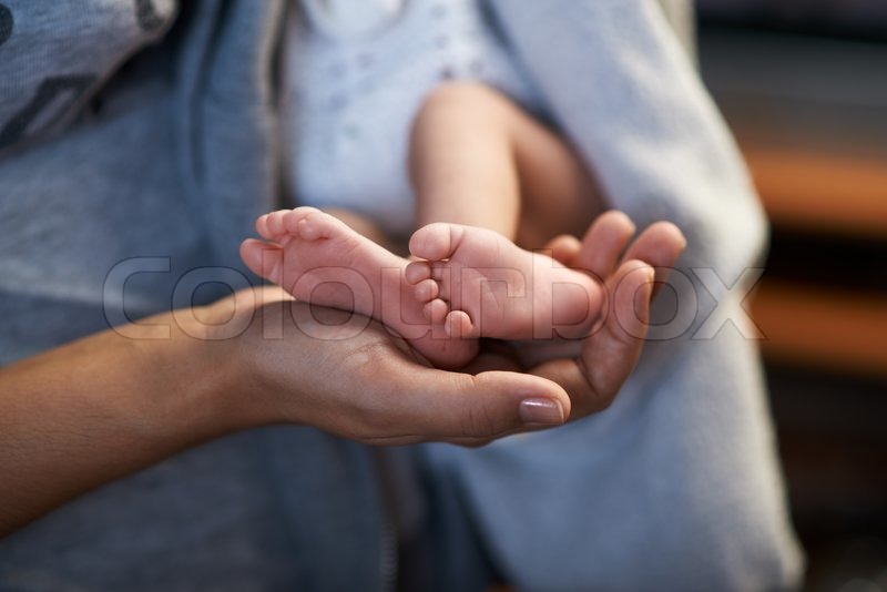 Mom keeps a miniature newborn feet in ... | Stock image | Colourbox