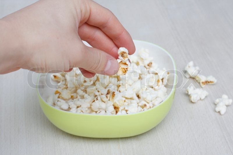 A hand getting hold of some popcorn | Stock image | Colourbox