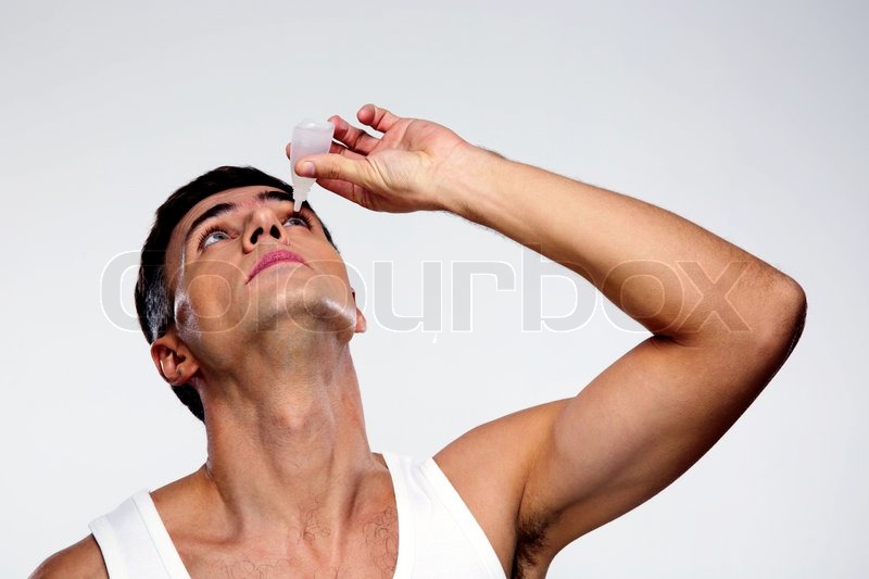 Handsome man applying eye drop over ... | Stock image | Colourbox