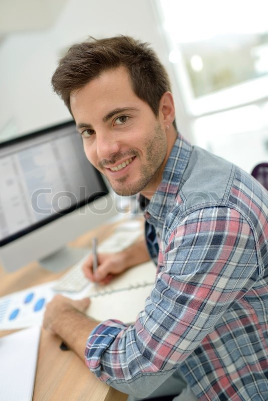 Smiling office worker sitting at desk | Stock image | Colourbox