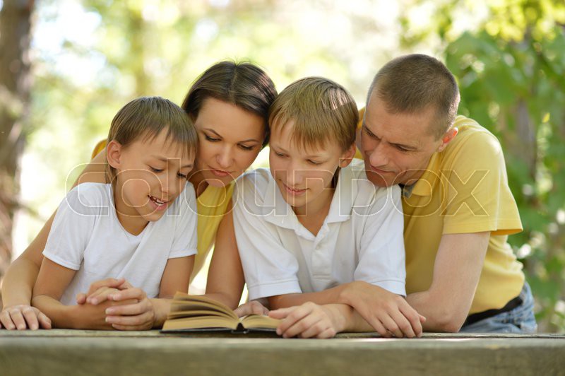 Happy family reading a book outdoors in ... | Stock image | Colourbox