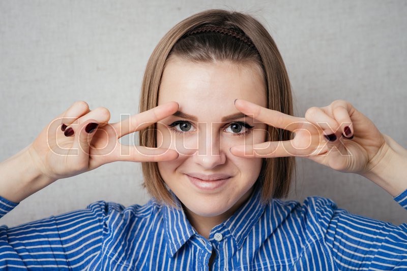 Girl shows two fingers around the eyes | Stock Photo | Colourbox