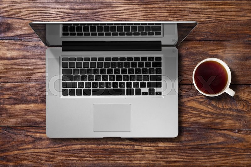 Open laptop and cup of tea on brown ... | Stock image | Colourbox
