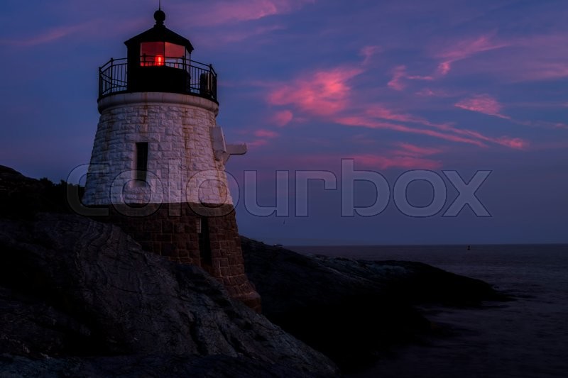 Lighthouse on a rocky shore at sunset. | Stock Photo | Colourbox