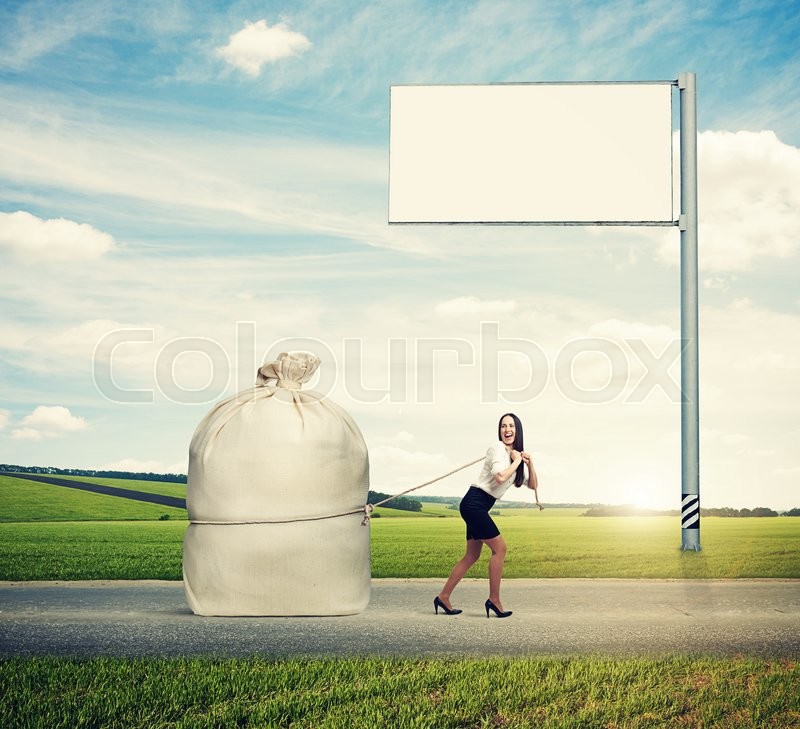 Laughing woman pulling big bag on the ... | Stock image | Colourbox