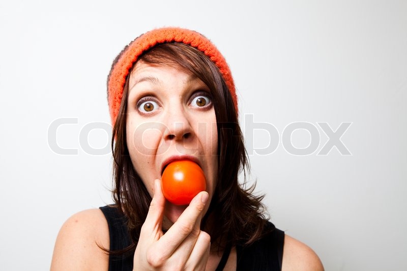 Young woman eating tomato. Funny facial ... | Stock image | Colourbox