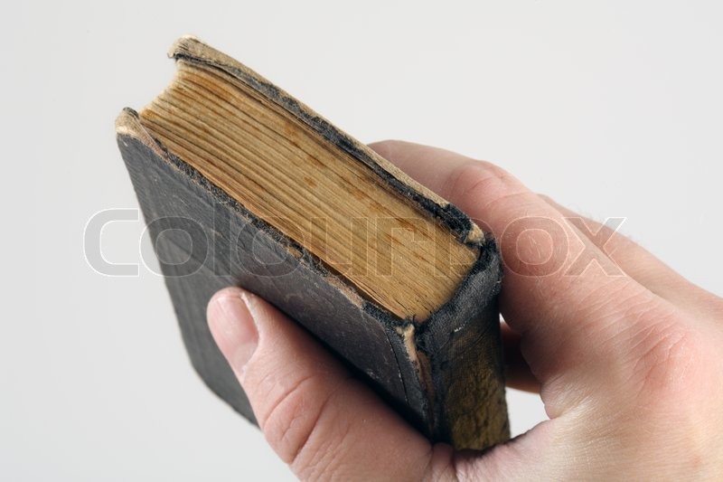 A hand grabbing an old small book | Stock image | Colourbox