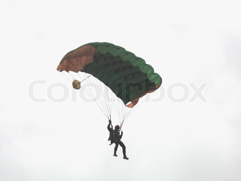Parachutist with a colourful parachute seen from below on a blue sky ...