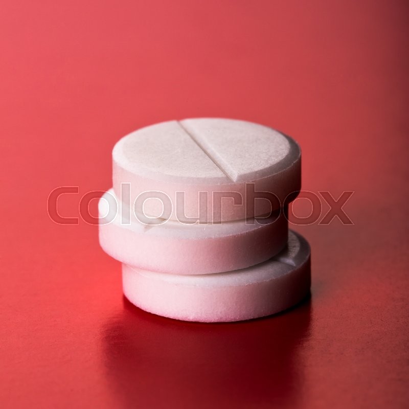 Closeup of three white tablets on red | Stock image | Colourbox