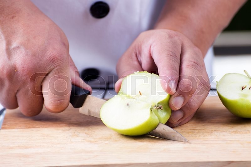 Chef's hands cutting green apple on ... | Stock image | Colourbox
