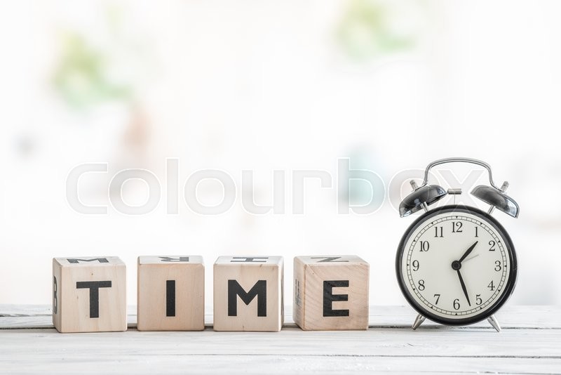 Alarm clock on a wooden desk with the word time | Stock Photo | Colourbox