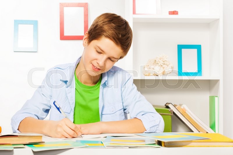 Nice handsome boy writing in textbook ... | Stock image | Colourbox