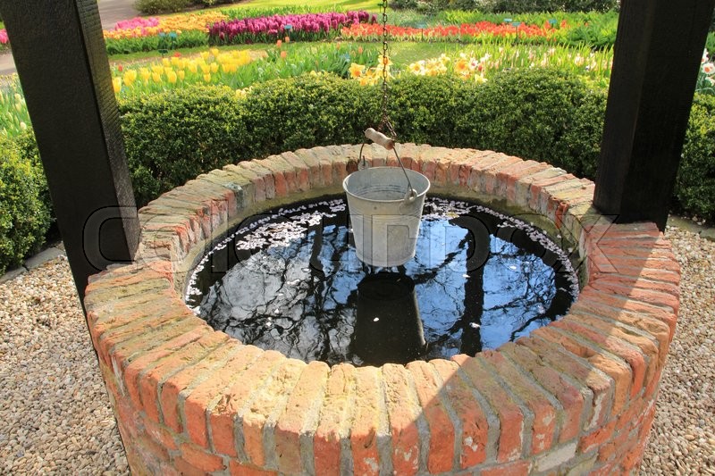 At the foreground a wishing well with a ... | Stock image | Colourbox