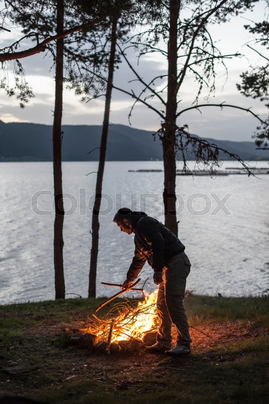 Man lights a fire in the fireplace in ... | Stock image | Colourbox