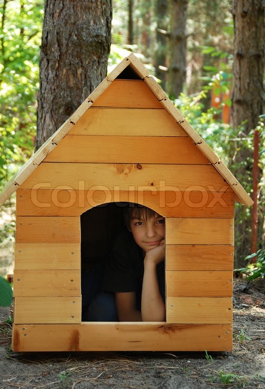 Kid sitting in a doghouse looking at ... | Stock image | Colourbox