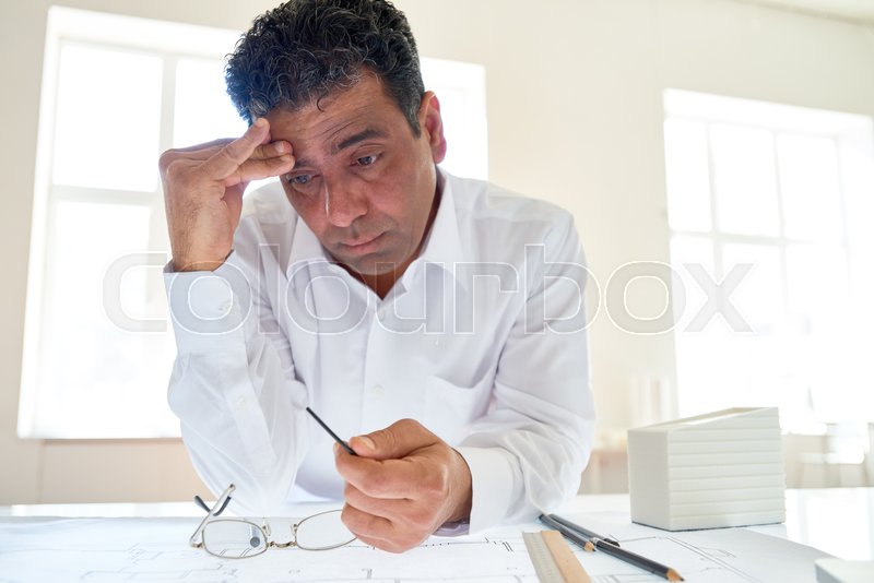 Pensive and tired engineer looking at ... | Stock image | Colourbox