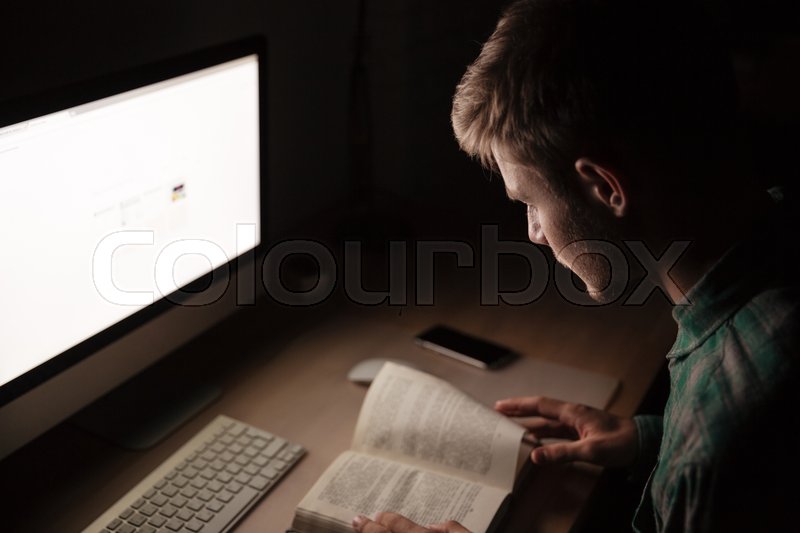Serious young man reading book and ... | Stock image | Colourbox