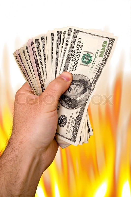 A hand full of cash over a fiery ... | Stock image | Colourbox