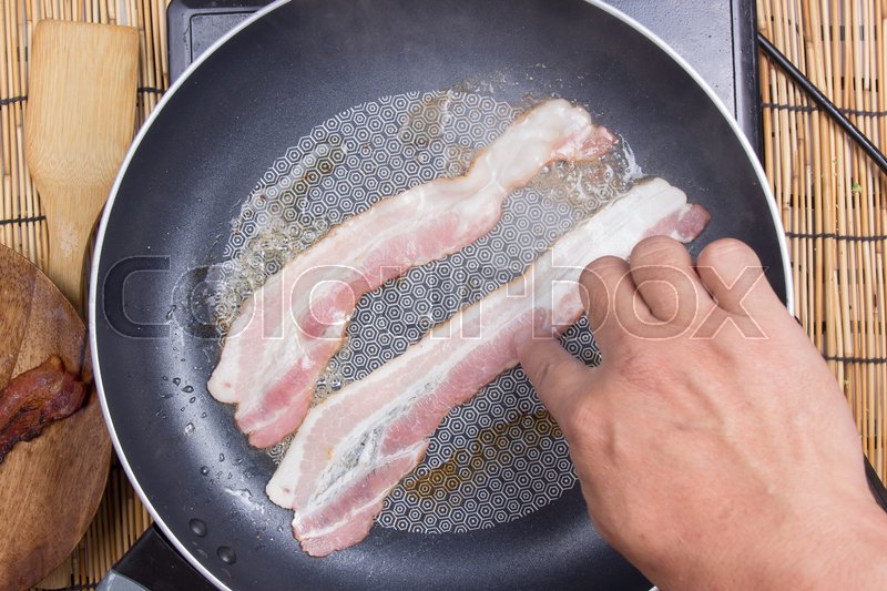 Chef frying bacon in the pan / cooking ... | Stock image | Colourbox