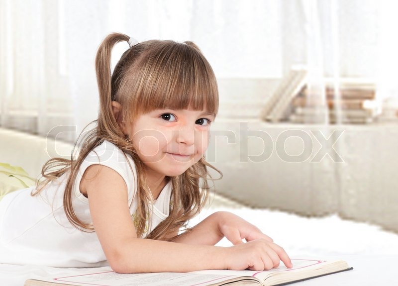 Lovely little girl, reading a book, on ... | Stock image | Colourbox