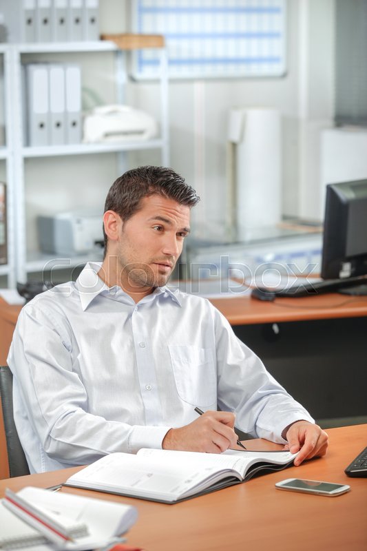 Man sat writing at his desk | Stock image | Colourbox