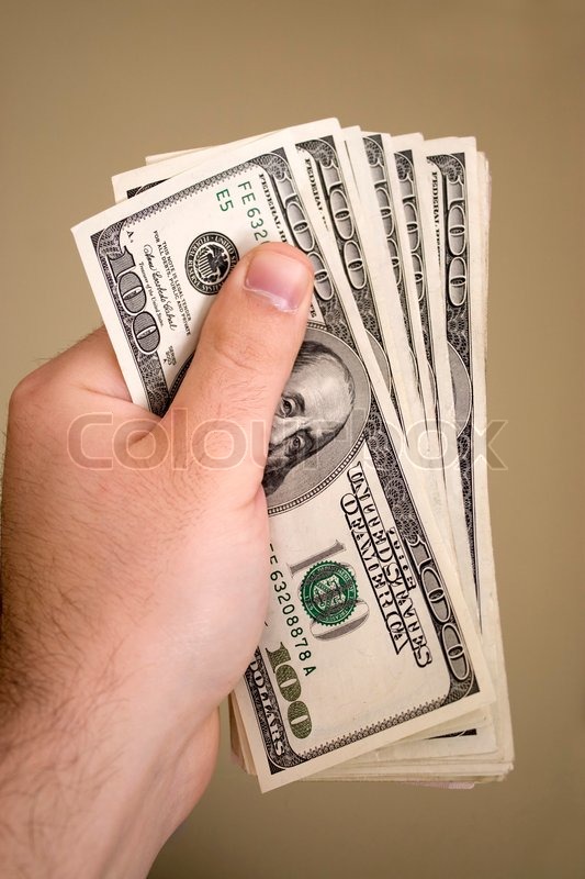 A handful of cash isolated over a gold ... | Stock image | Colourbox