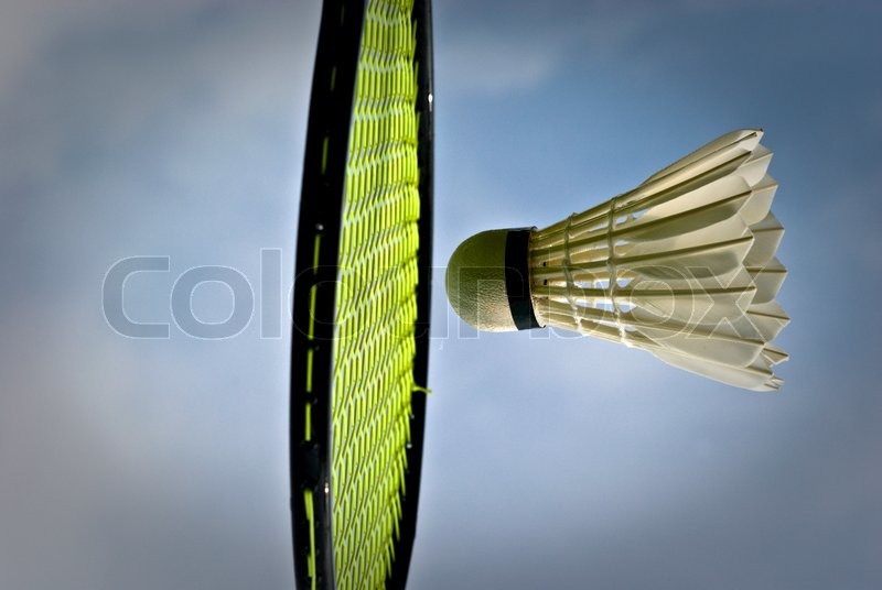 Hit the shuttlecock outdoors a sunny day with the badminton racket ...