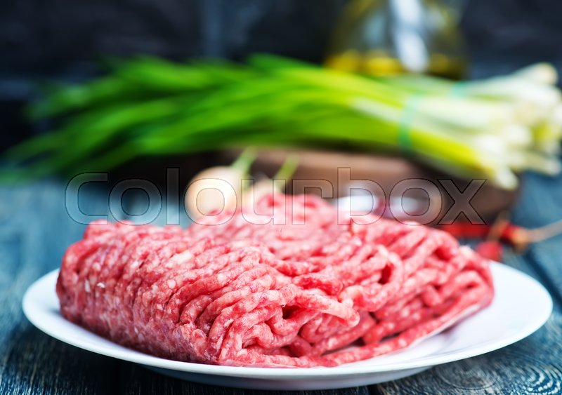 Raw minced meat on plate and on a table | Stock image | Colourbox