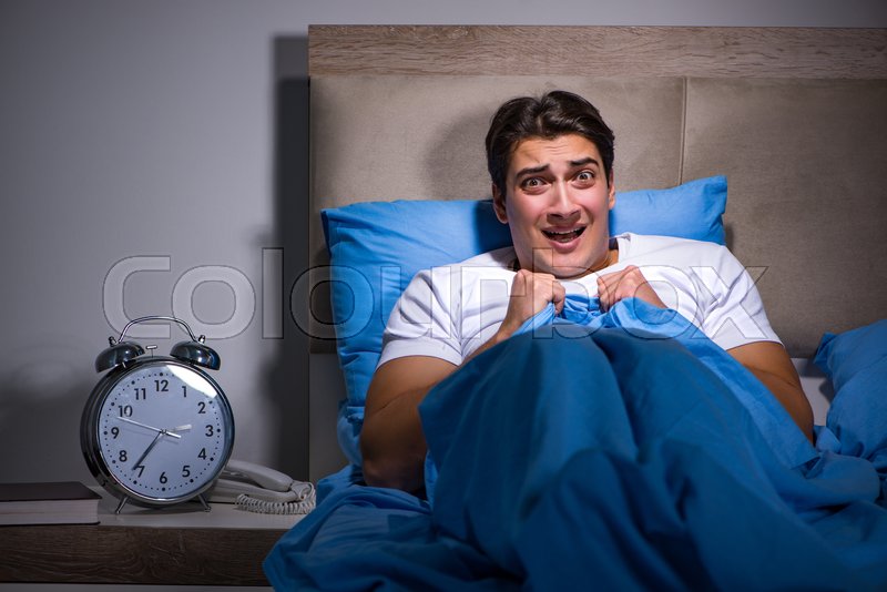Young man scared in bed | Stock image | Colourbox