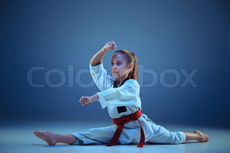 Young girl training karate on blue ... | Stock image | Colourbox