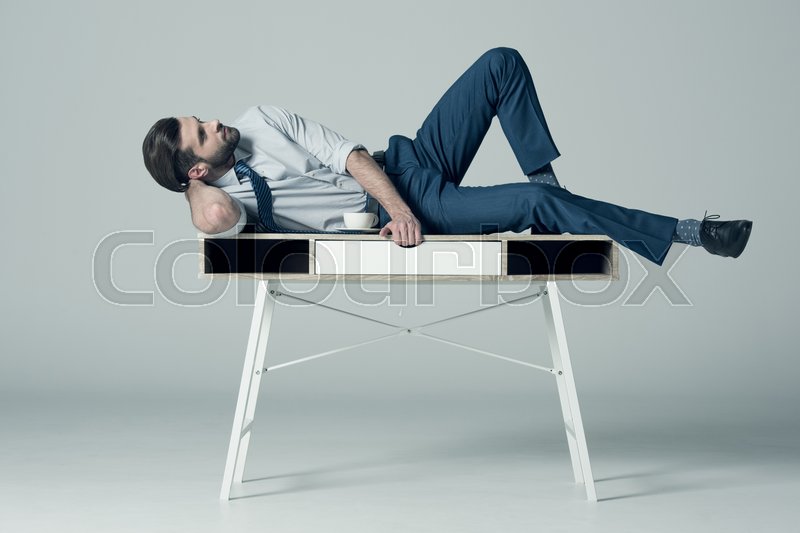 Side view of businessman lying on table ... | Stock image | Colourbox