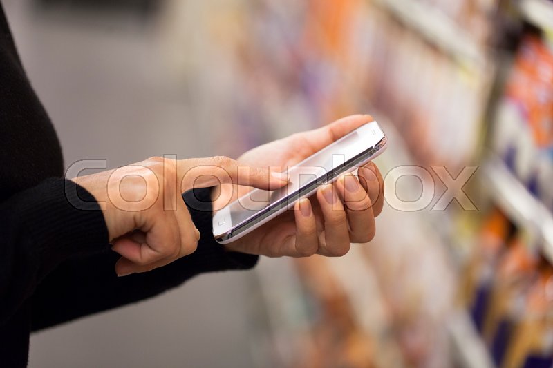 Woman using mobile phone while shopping ... | Stock image | Colourbox