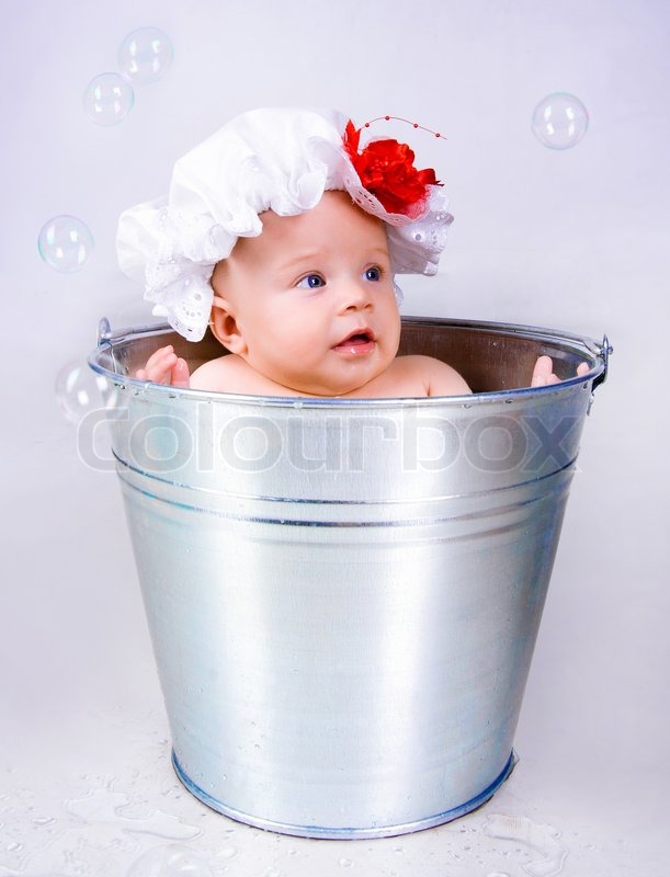 Little baby on a bucket on white ... | Stock image | Colourbox