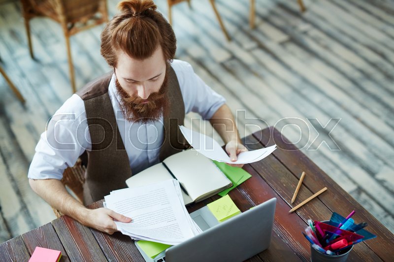 Young man with papers reading data ... | Stock image | Colourbox