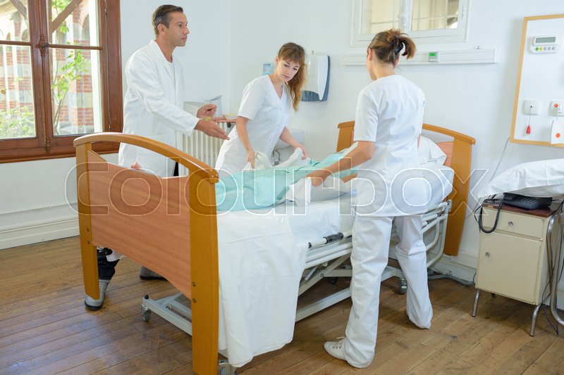 Nurses lifting patient under doctor's ... | Stock image | Colourbox