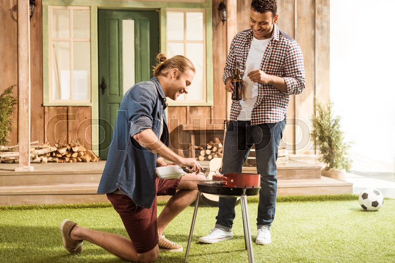 Two men grilling burgers while talking ... | Stock image | Colourbox