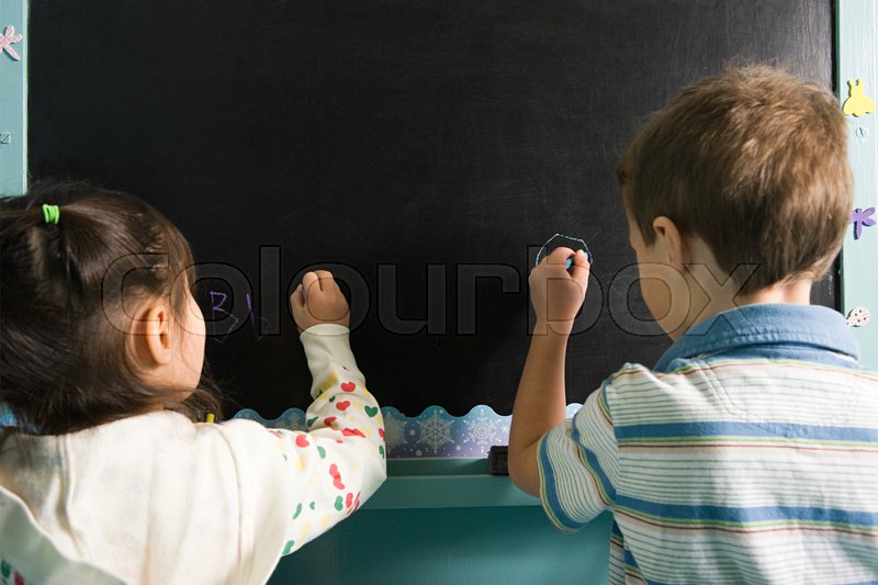 Children writing on a blackboard | Stock image | Colourbox