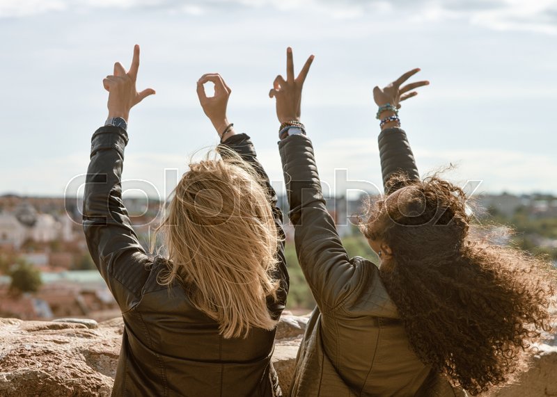 Two girls showing love sign by their ... | Stock image | Colourbox