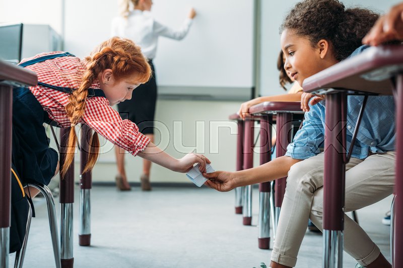 Schoolgirls passing message in class on ... | Stock image | Colourbox