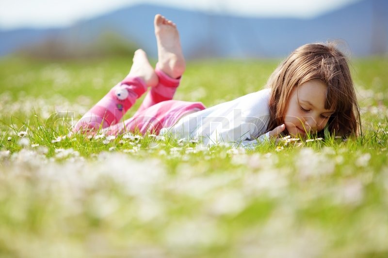 Kid girl resting in grass at spring | Stock image | Colourbox
