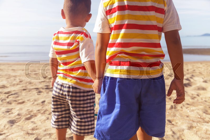 Two baby (brothers) holding hands on ... | Stock image | Colourbox