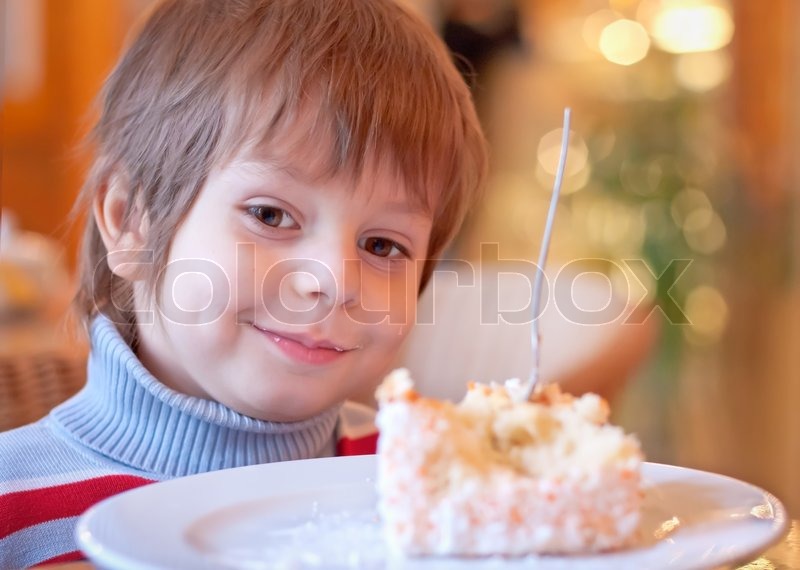 Smiling young boy eating piece of cake ... | Stock image | Colourbox