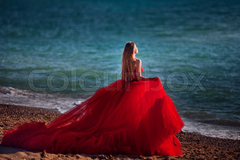 A woman in a red dress on the beach. ... | Stock image | Colourbox